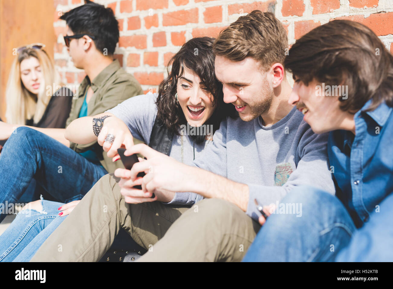 Group of young multiethnic friends sitting on the floor chatting to ...