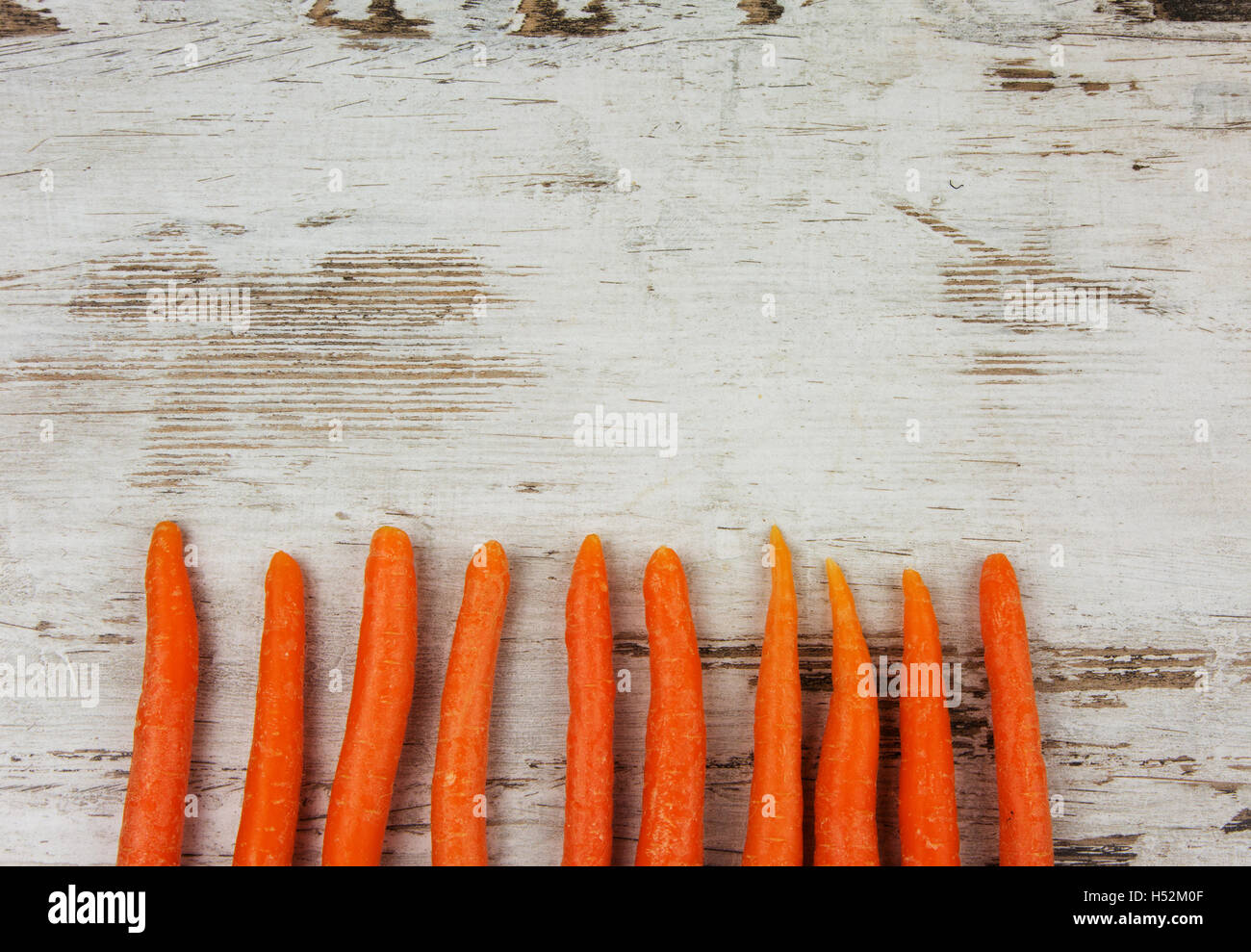 Old, bright wooden countertop with ten carrots along the bottom edge ...