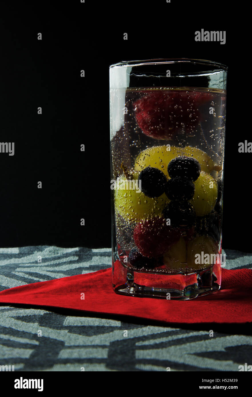 Sparkling water with raspberries, blueberries and grapes in a high ...