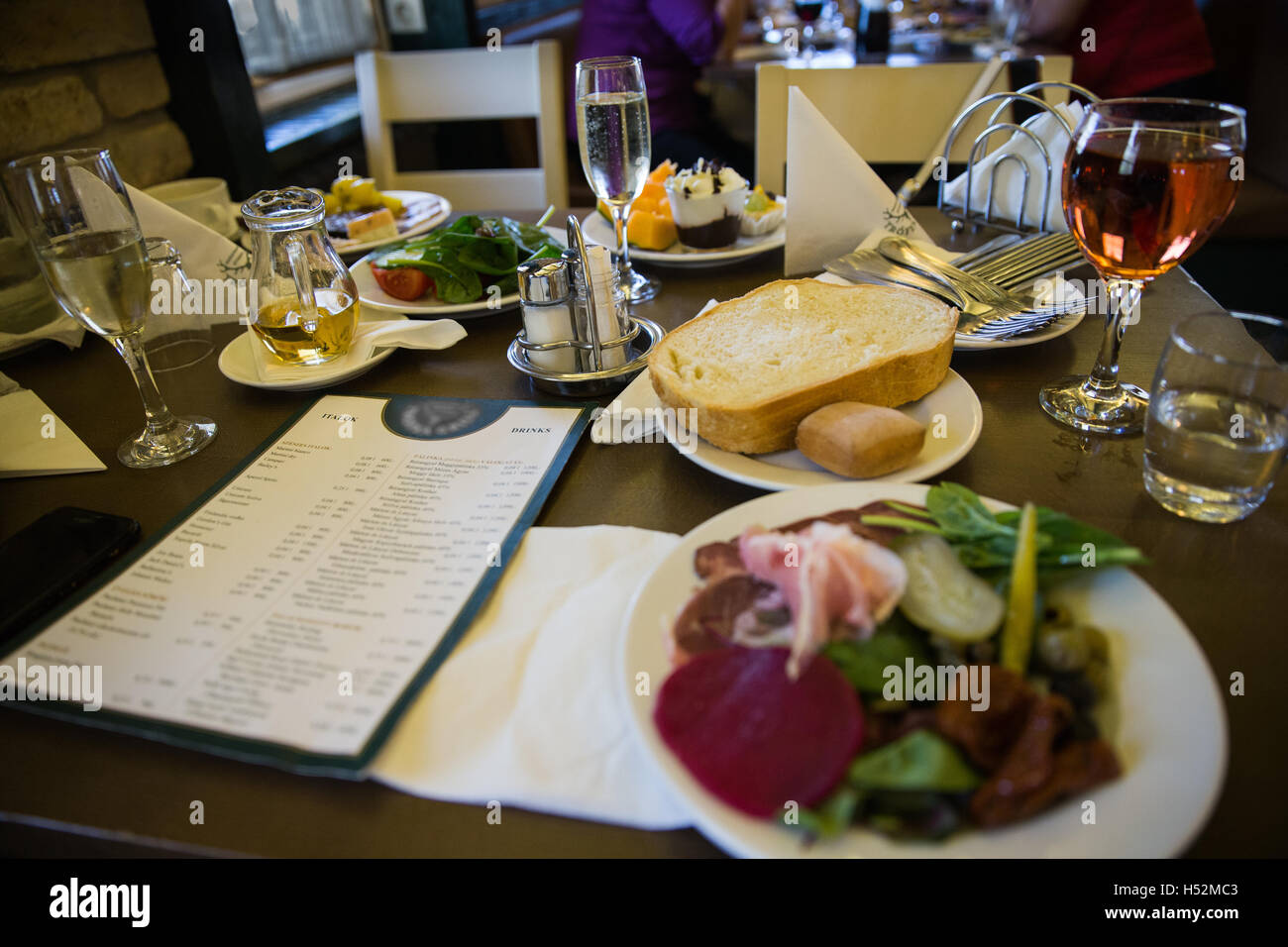 The table in cafe with salads and menu. Wine by the glass, bread on the ...
