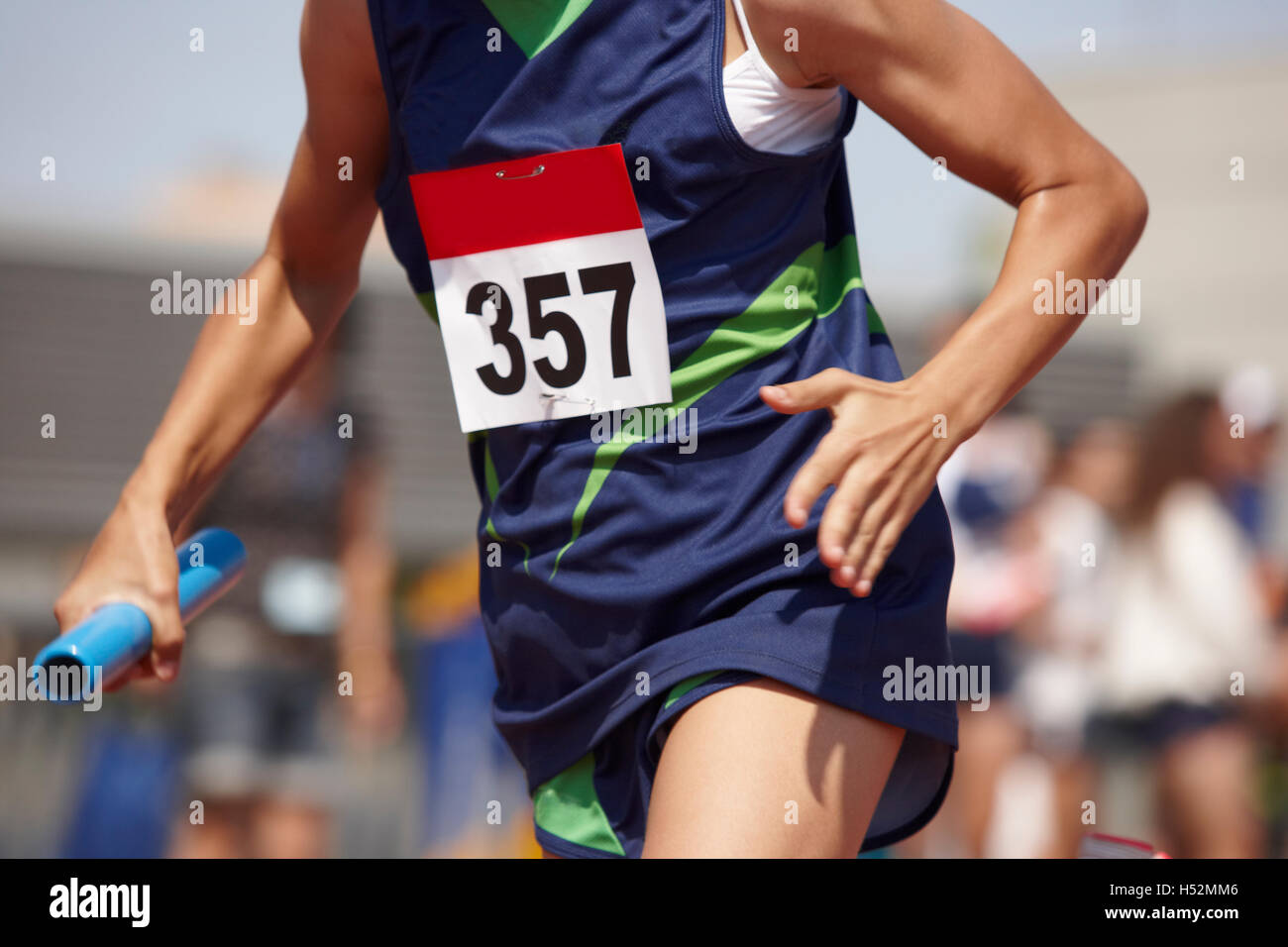 Female runner finalizing a relay race in a running track. Horizontal ...