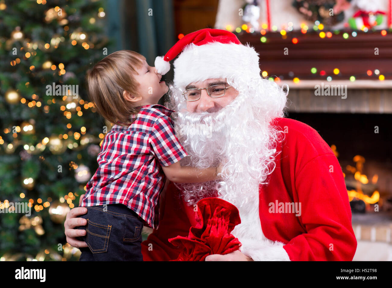 Santa Claus and child with presents at fireplace. Kid boy and father in ...