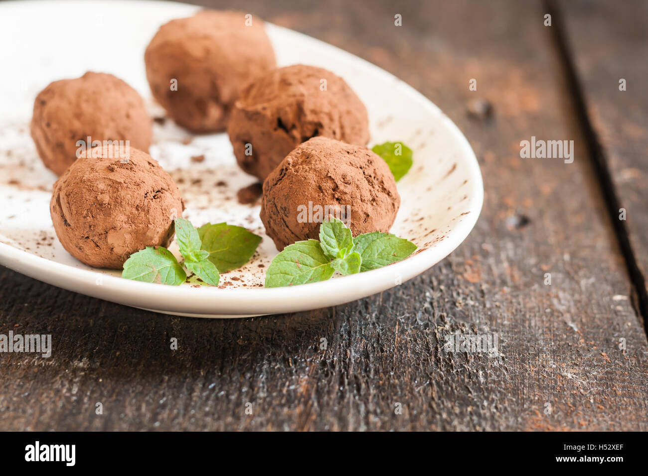 dessert truffles sprinkled with cocoa and mint on a white plate Stock ...
