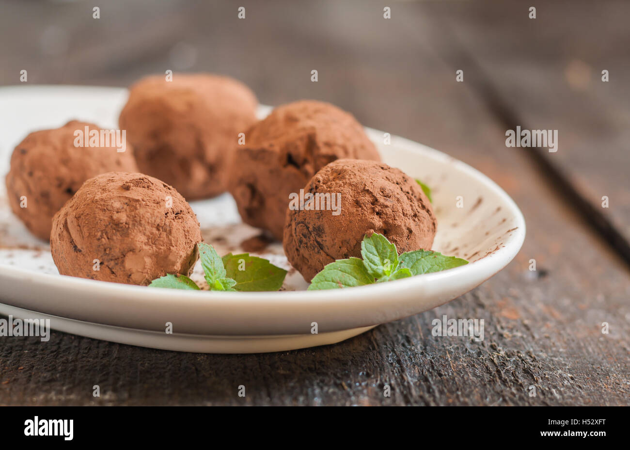 dessert truffles sprinkled with cocoa and mint on a white plate Stock ...