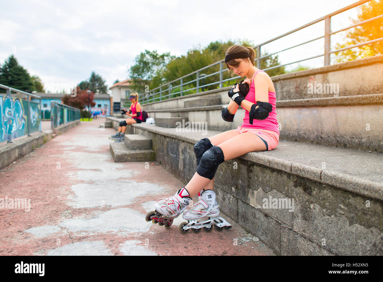Girls are preparing to do rollerblading on the steps of the field Stock ...