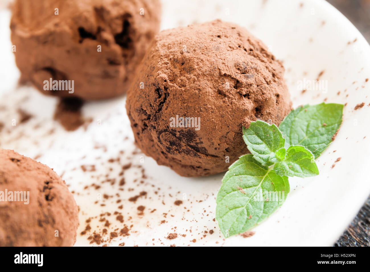 dessert truffles sprinkled with cocoa and mint on a white plate Stock ...
