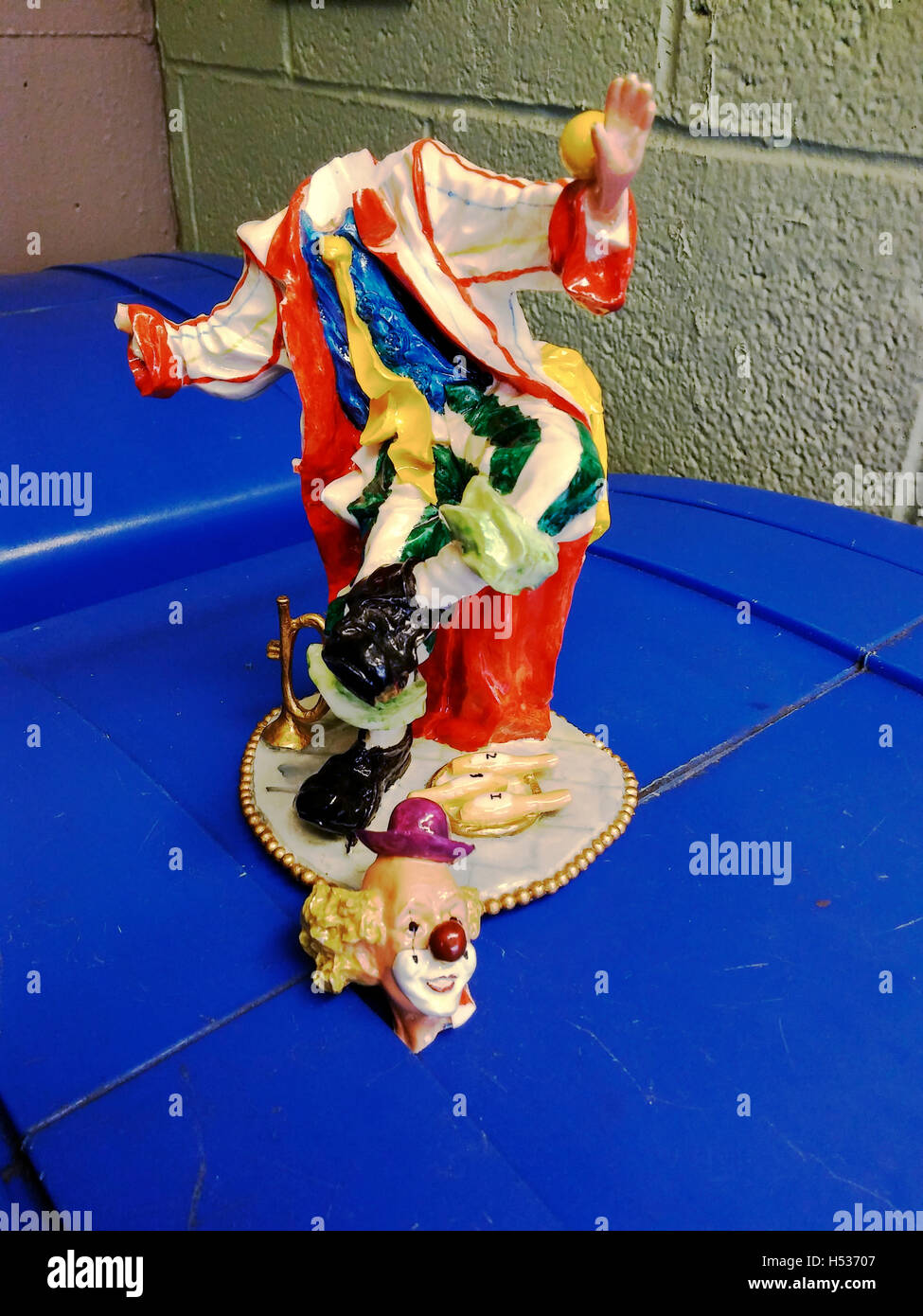 Broken clown sculpture seen in the trash area of an apartment building ...
