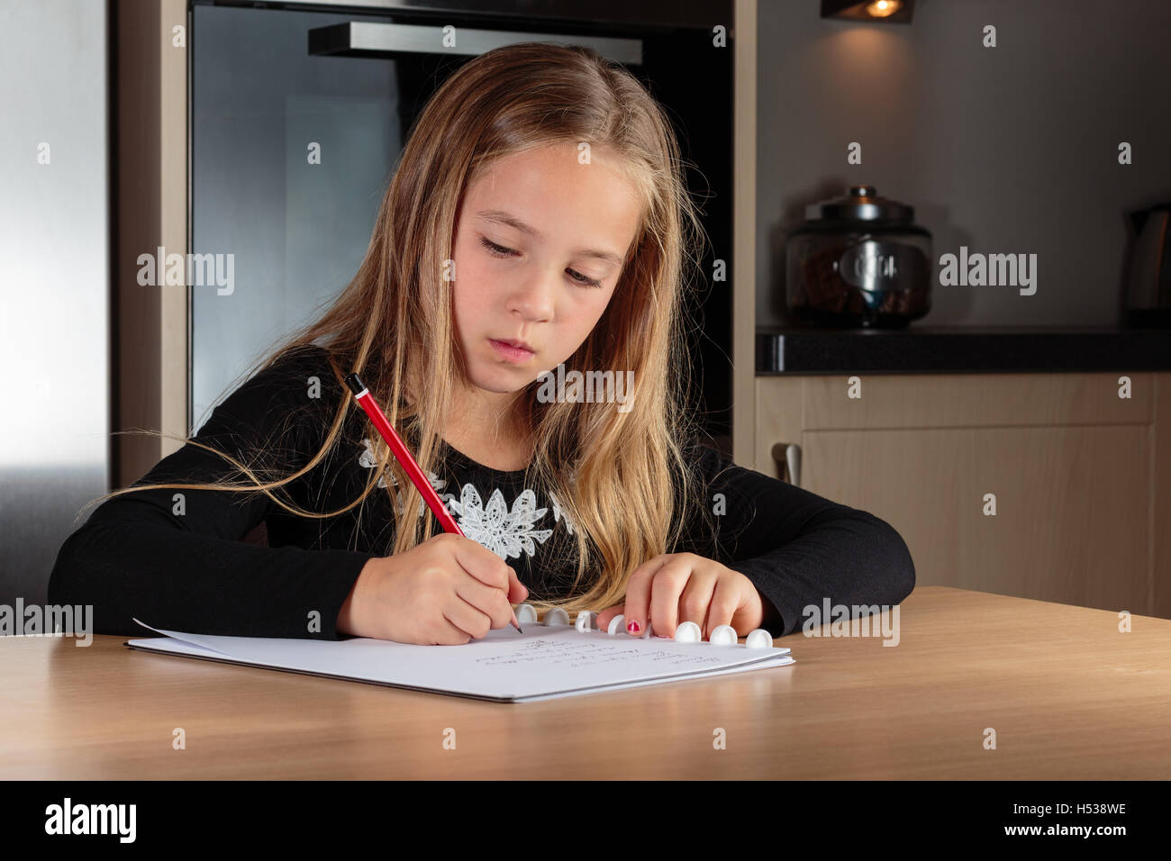 Girl doing homework at the kitchen table Stock Photo - Alamy