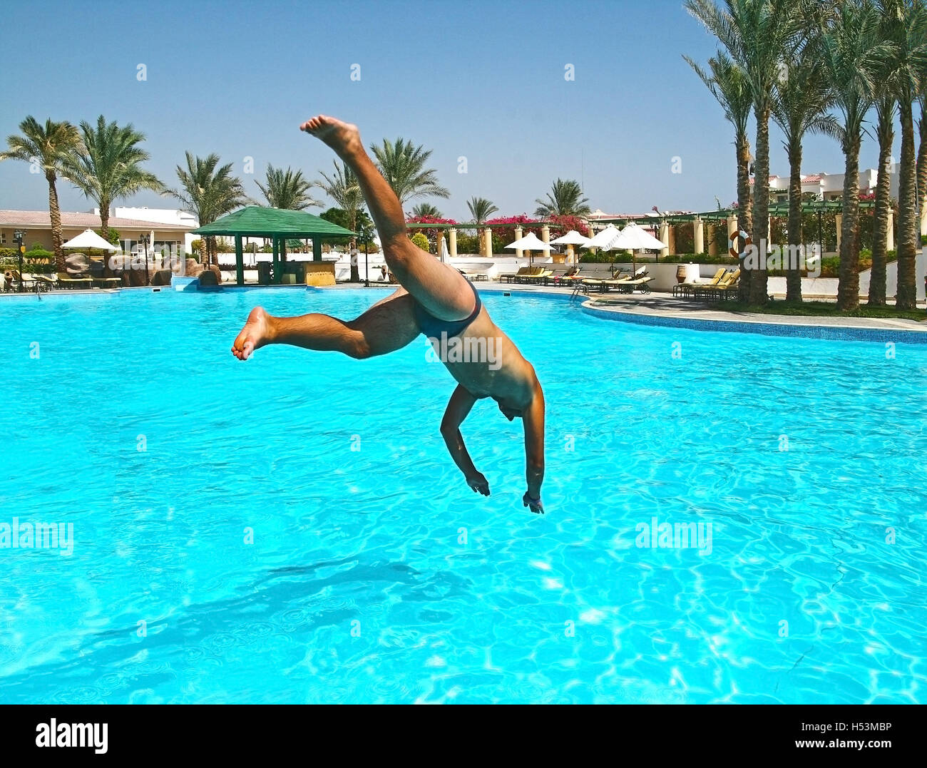 man jumps into the pool at a tropical resort Stock Photo - Alamy