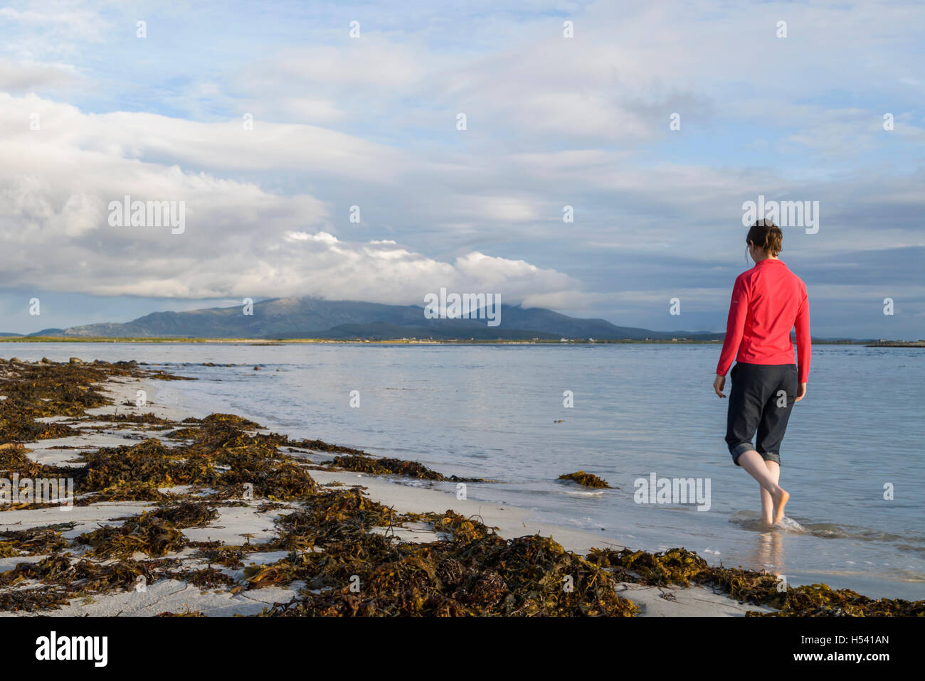 Female paddlling in the sea along Liniclate Beach on Benbecula with ...
