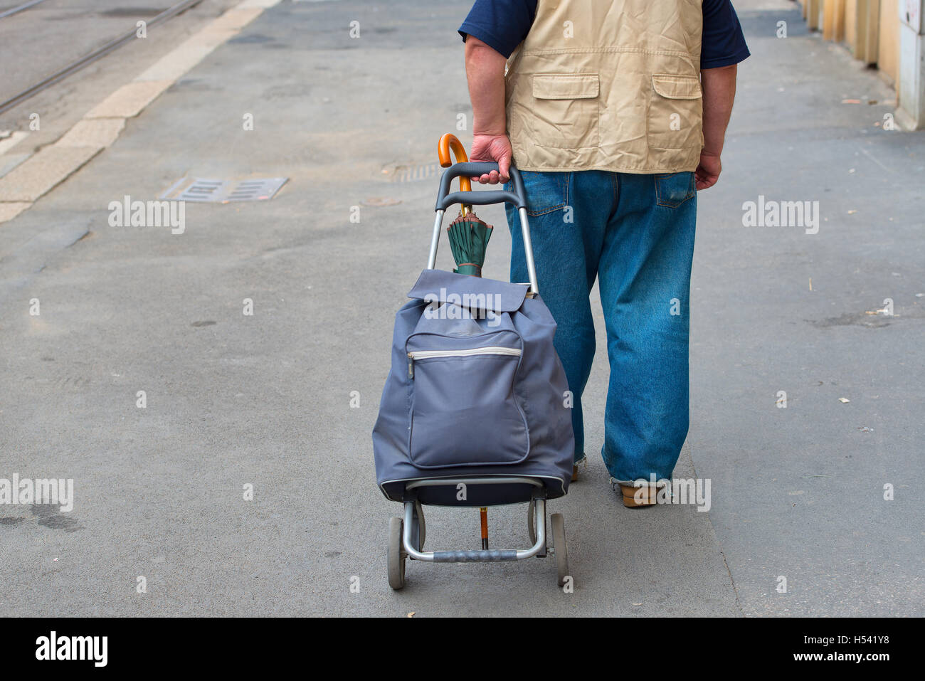 Elderly man with shopping cart dragged on the pavement Stock Photo - Alamy