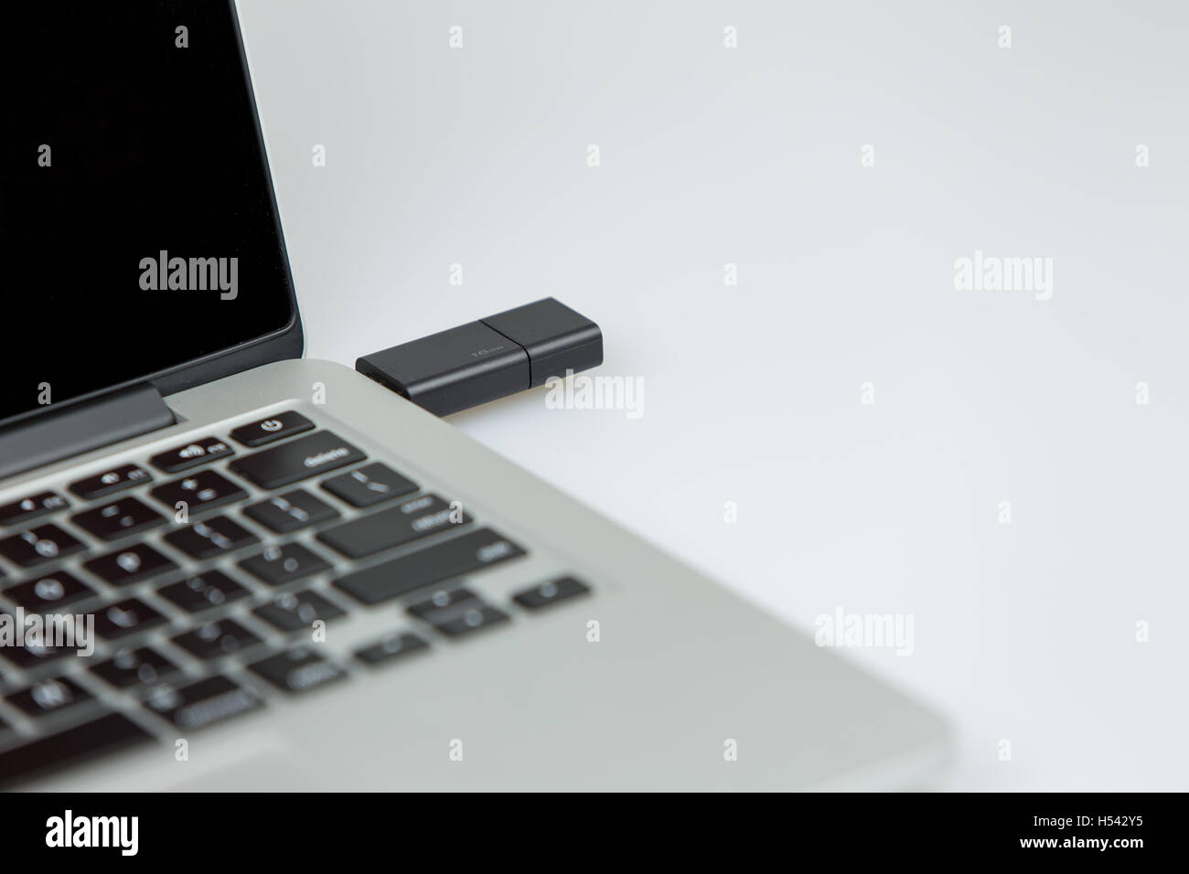 a 16gb black usb stick plugged on right side of laptop. closeup shot ...