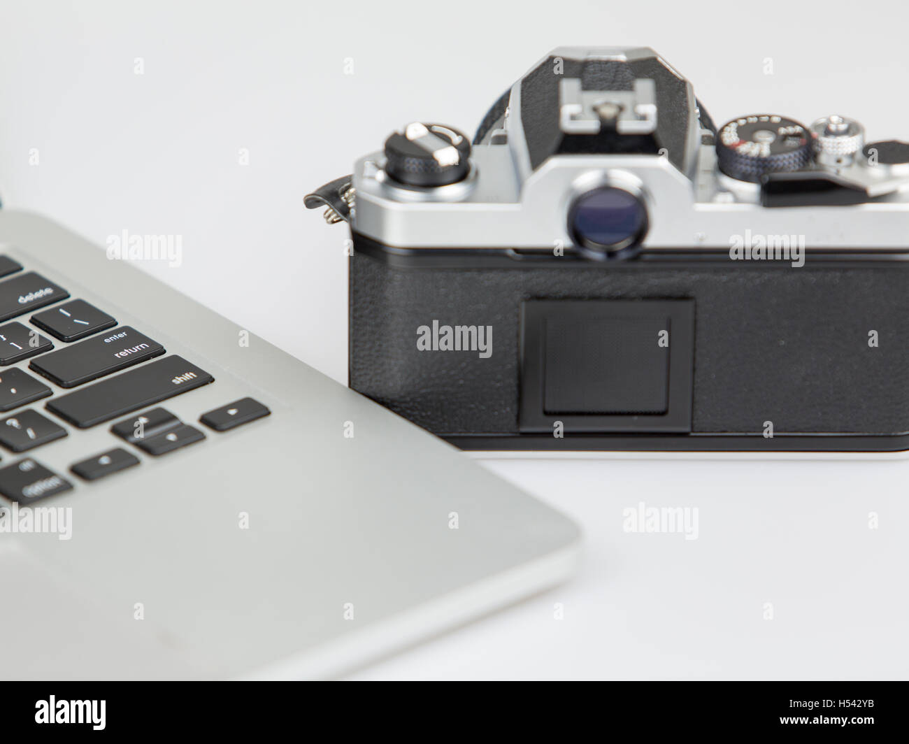 vintage camera and a laptop on a white table with white background ...