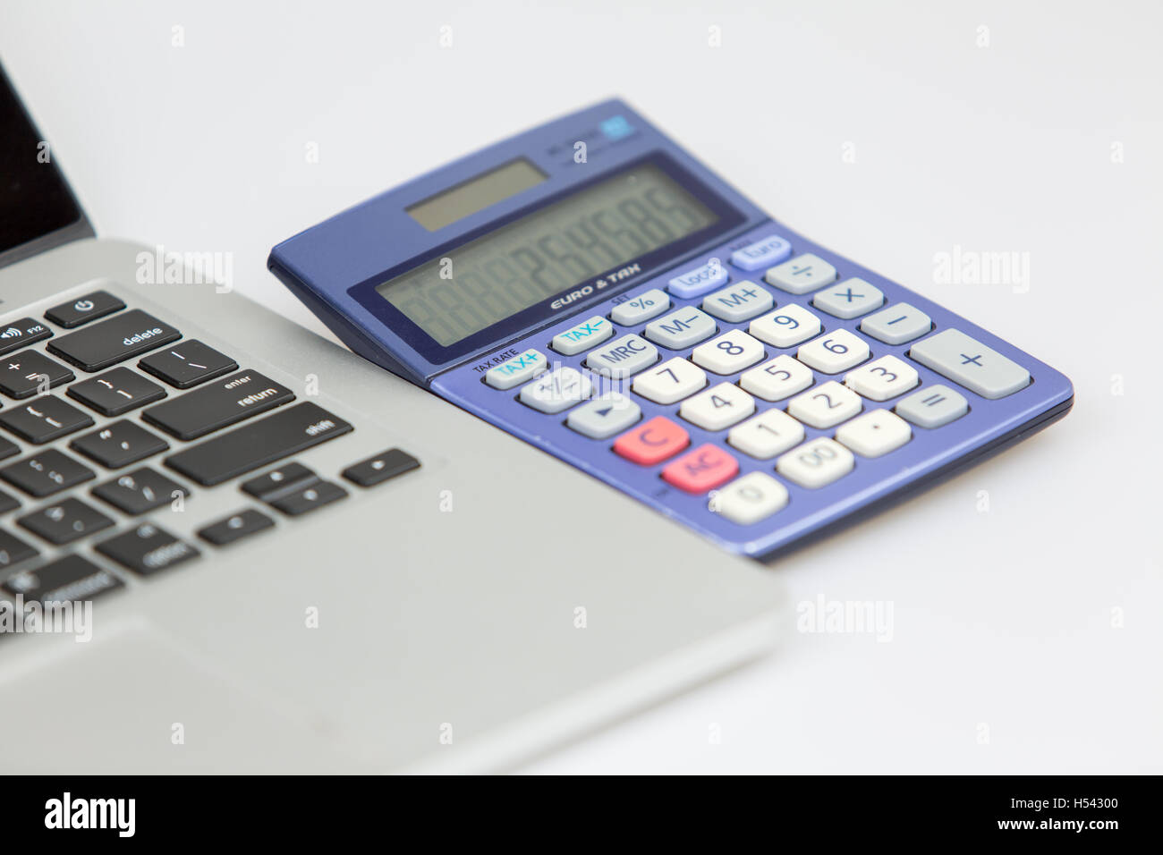 laptop and calculator on a white background. digits appearing on ...