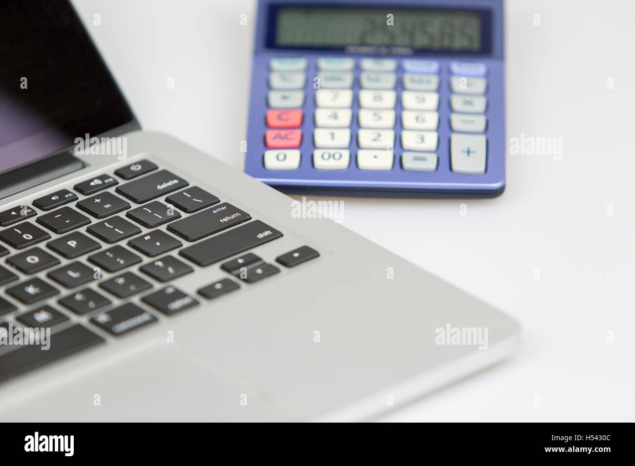 laptop and calculator on a white background. digits appearing on ...