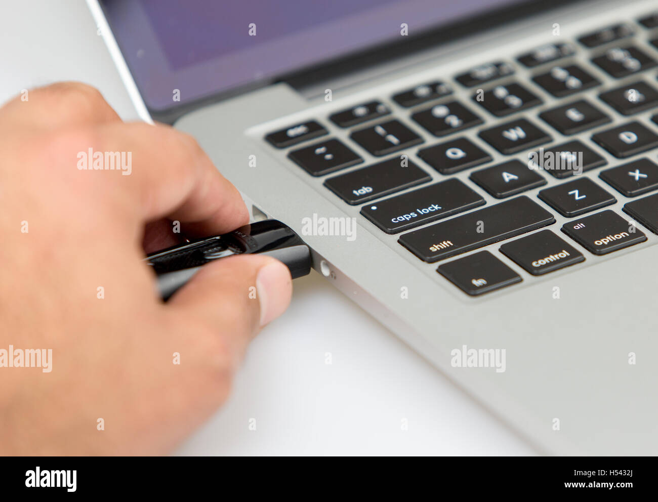 A male person plugging USB data traveller stick into a laptop. closeup ...