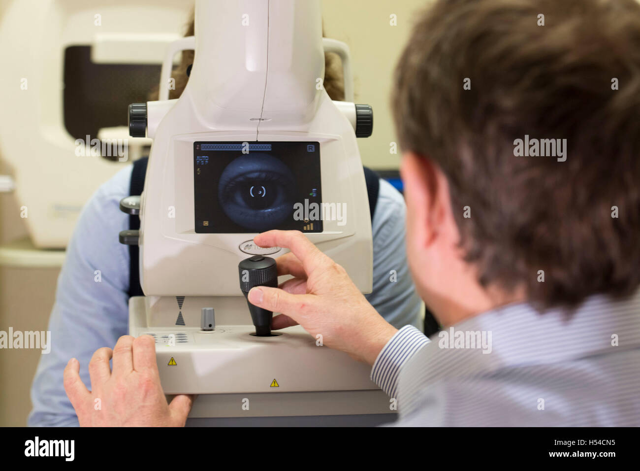 An optician carrying out an eye test using a Optical Coherence ...