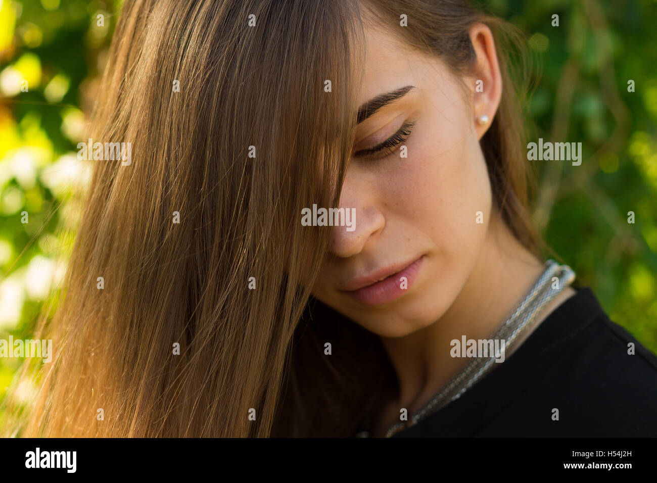 Young woman looking down on the background of trees Stock Photo - Alamy