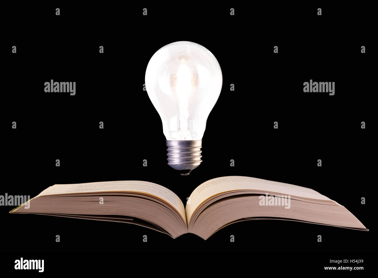 lamp bulb light floating over open book against black background Stock Photo - Alamy