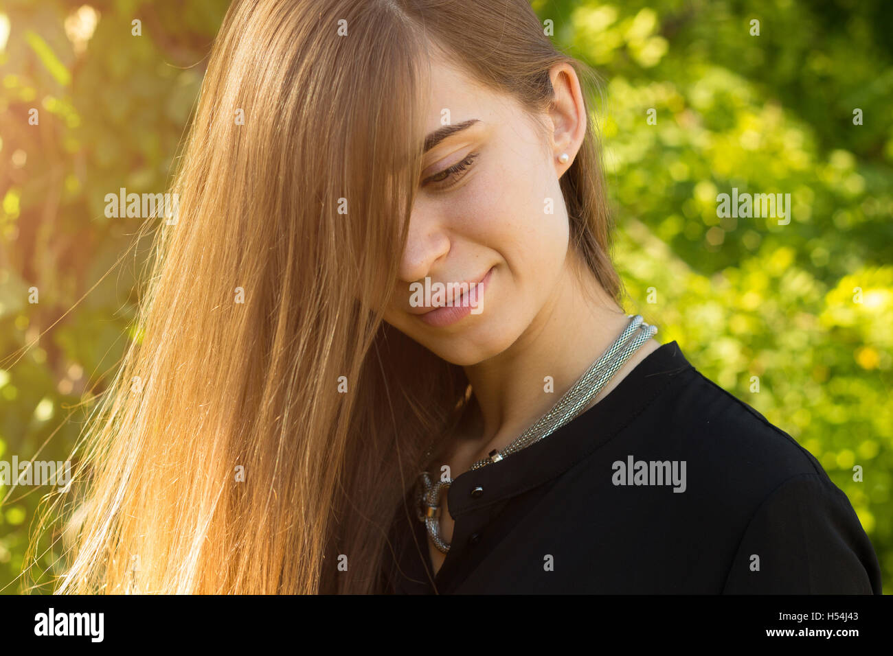 Young woman looking down on the background of trees Stock Photo - Alamy