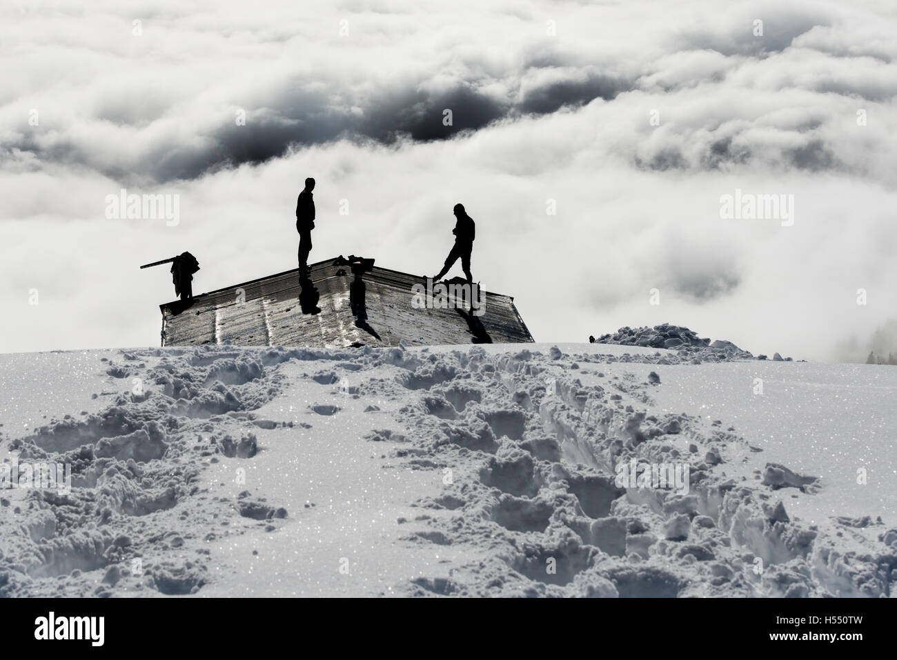 Men shoveling snow from the roof of the house Stock Photo - Alamy