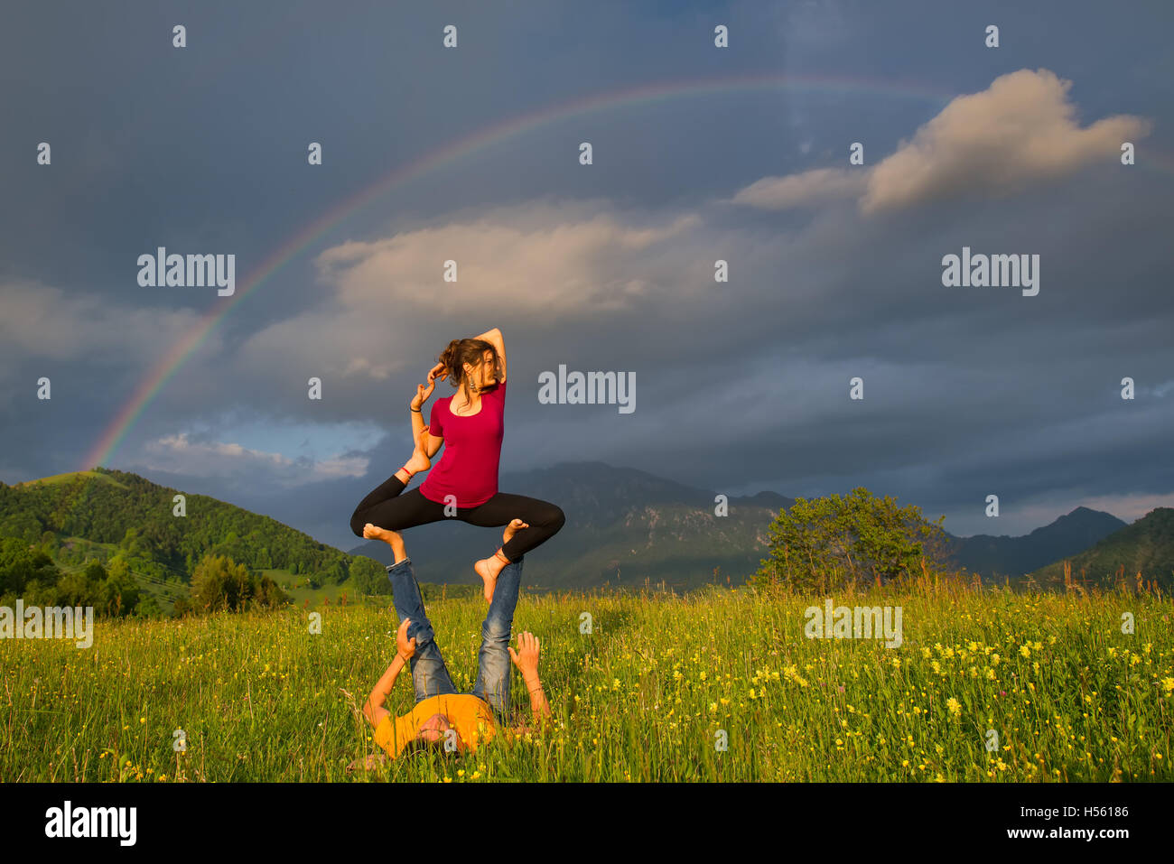 Positions Acroyoga girl of male in nature in the mountains with rainbow ...