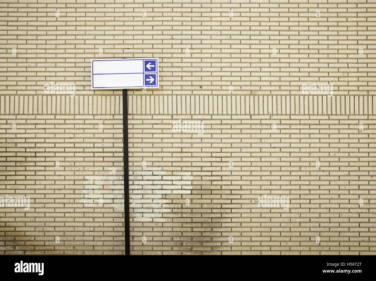 Information sign with arrows, detail of a brick wall with a signal ...