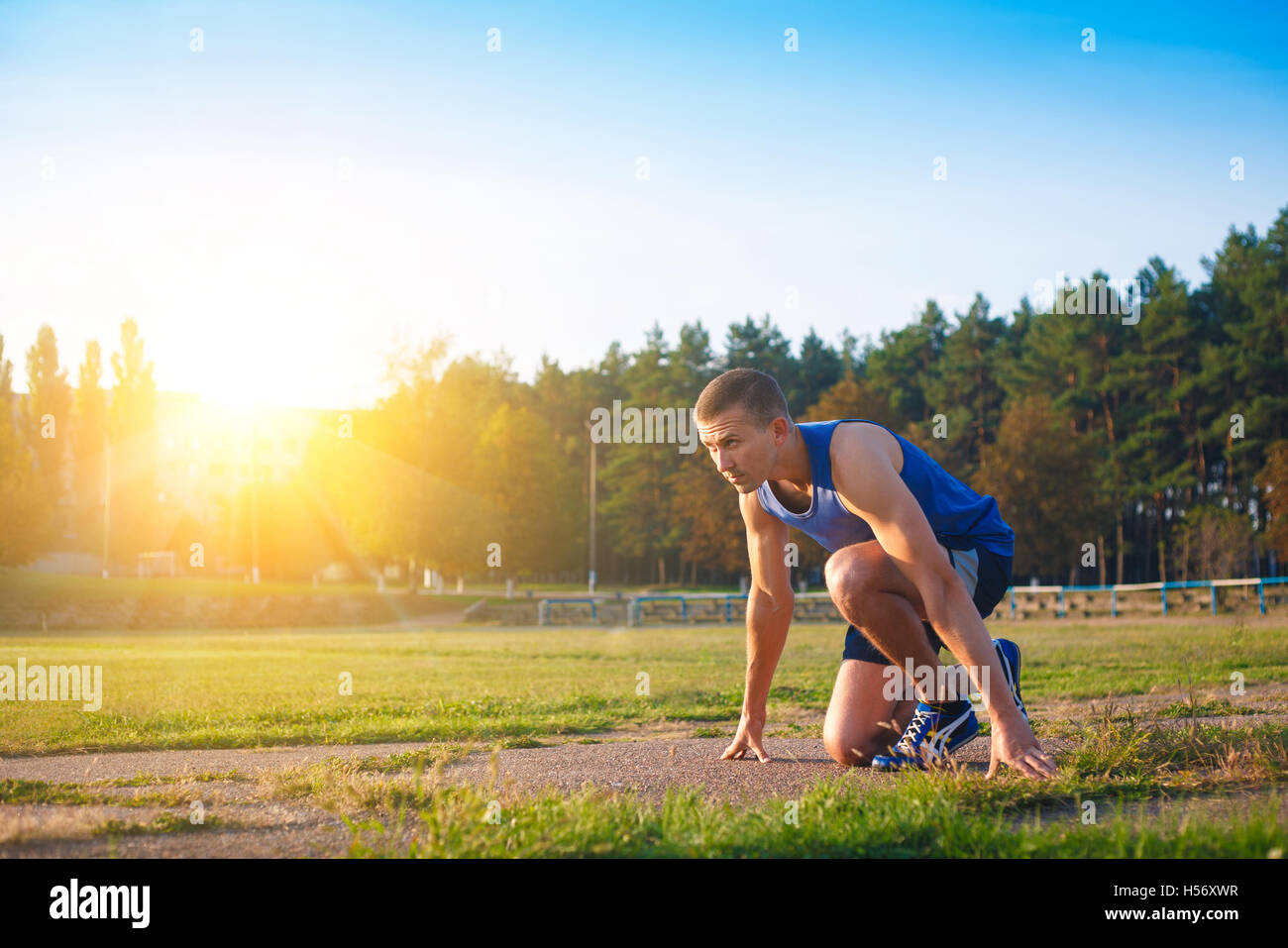 Man in low start position on old stadium. Athlete in starting position ...