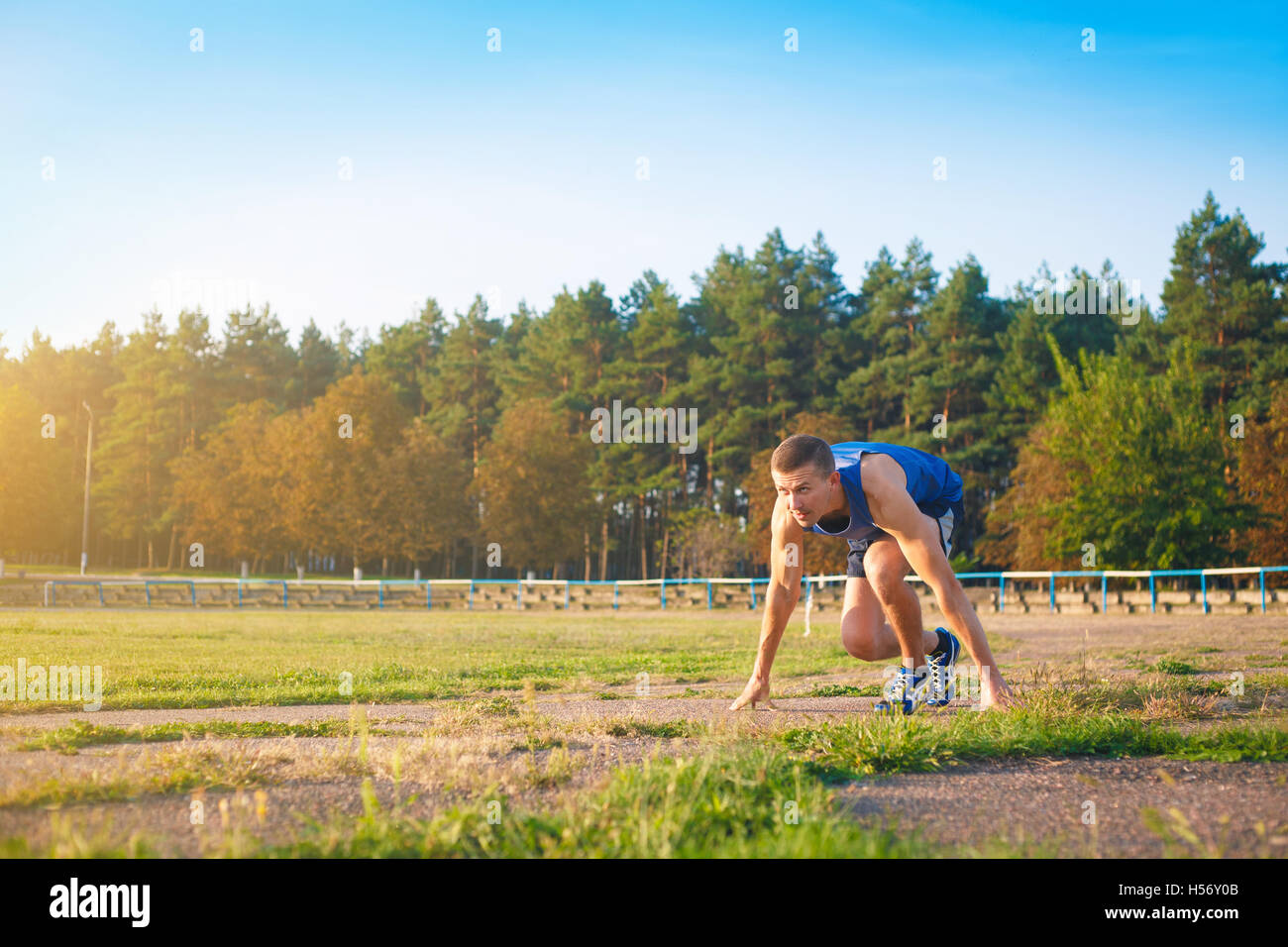 Man in low start position on old stadium. Athlete in starting position ...