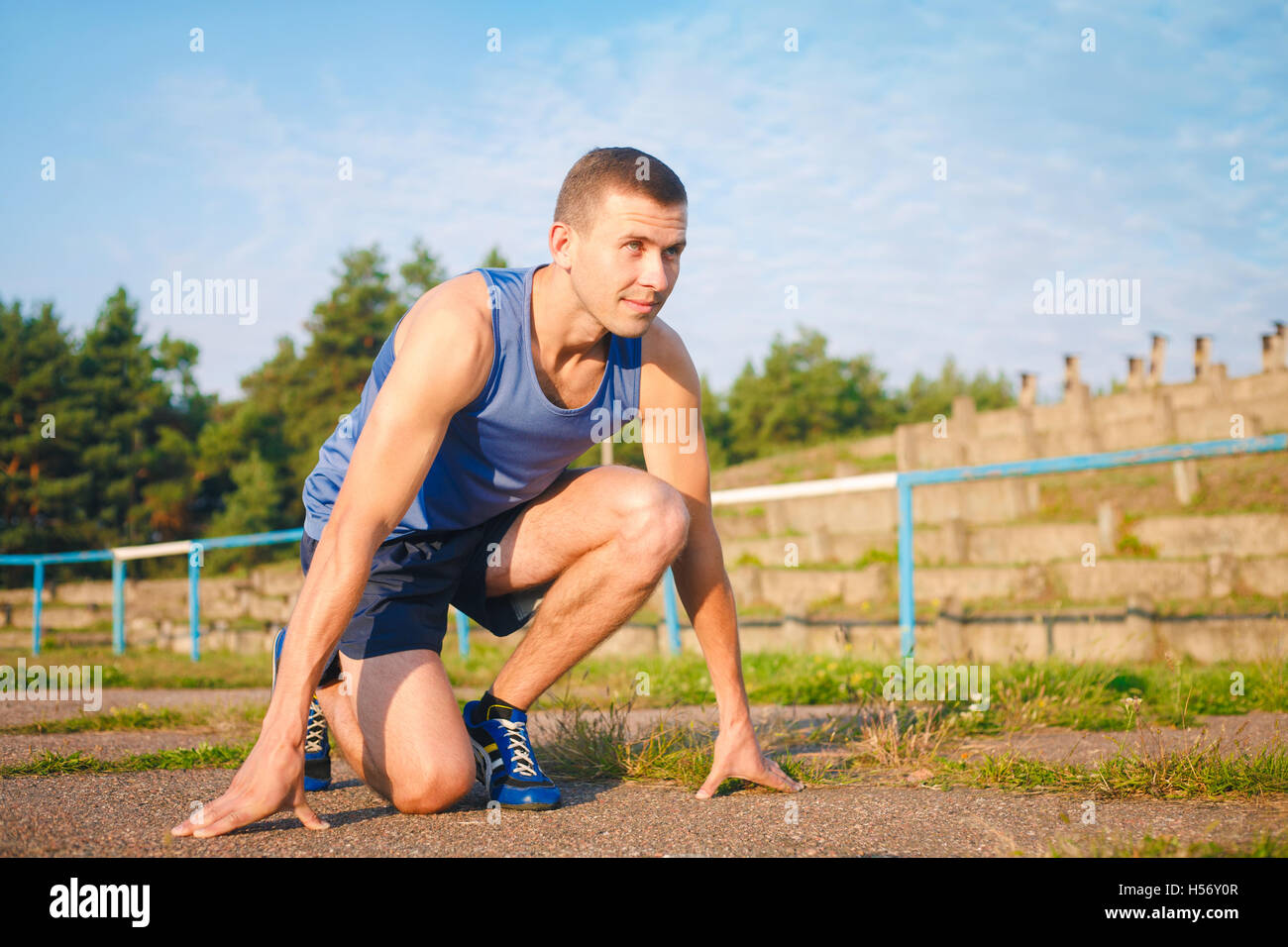Man in low start position on old stadium. Athlete in starting position ...