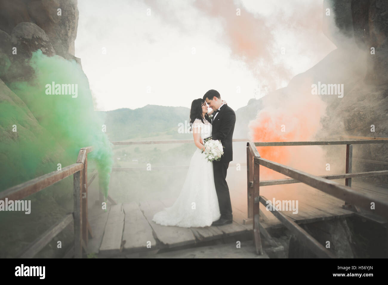 Wedding couple posing near rocks with colored smoke behind them Stock ...