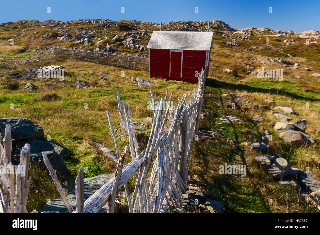 A rocky field with a traditional wooden enclosure in rural Newfoundland ...