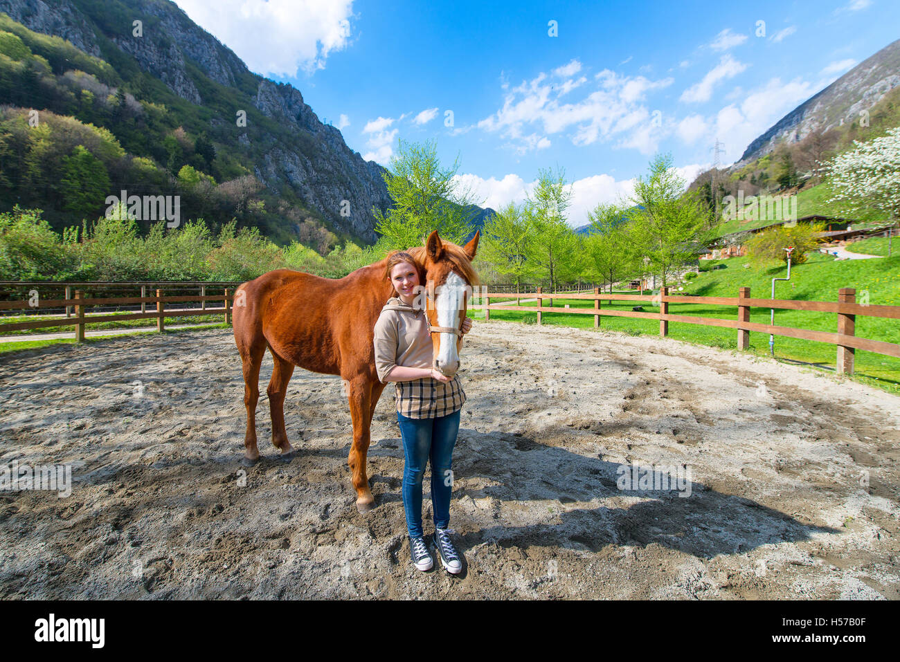 Standing girl in the paddock with a horse in a beautiful spring day ...