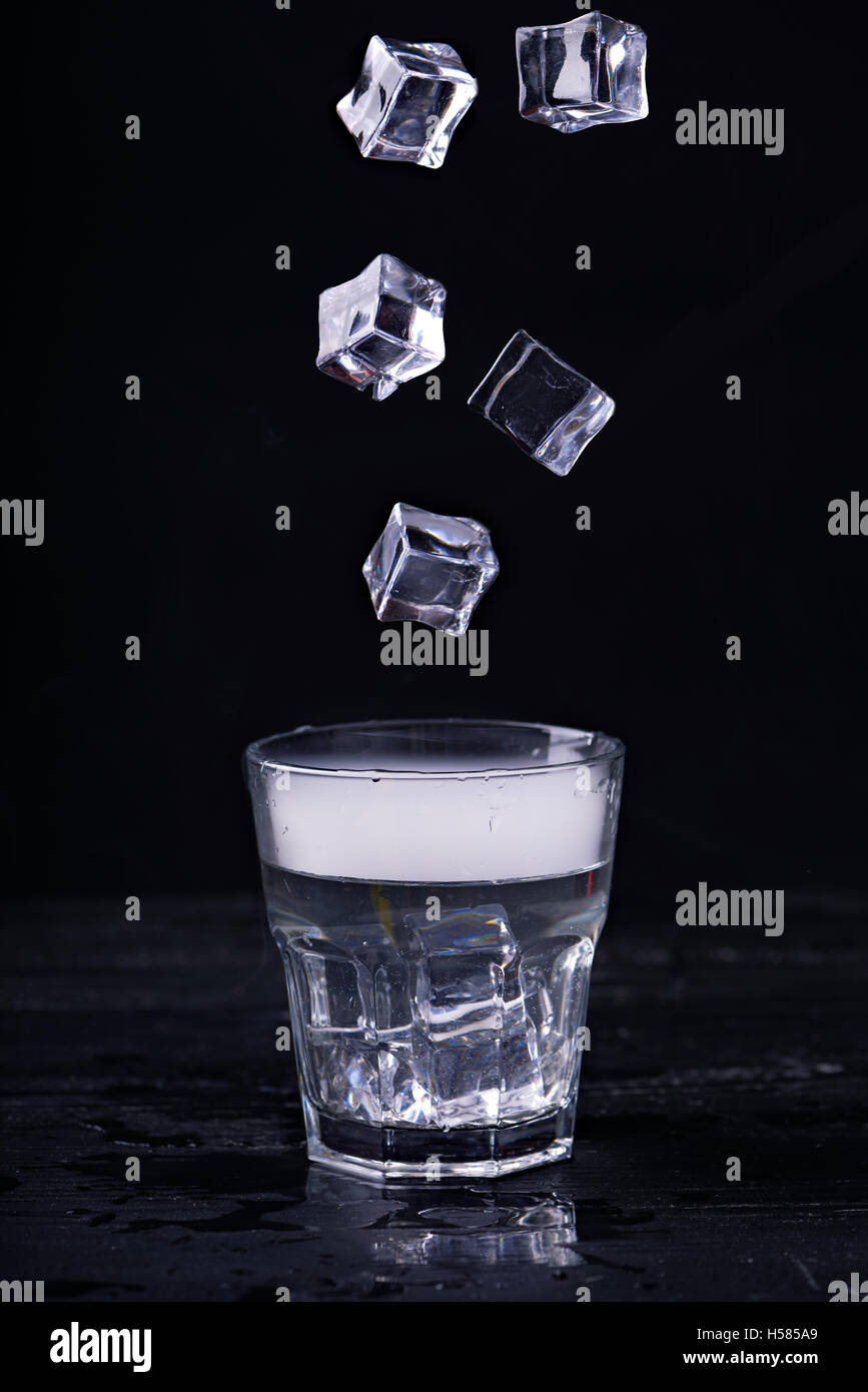 Hot water with a lot of steam in a glass and ice cubes in motion at a ...