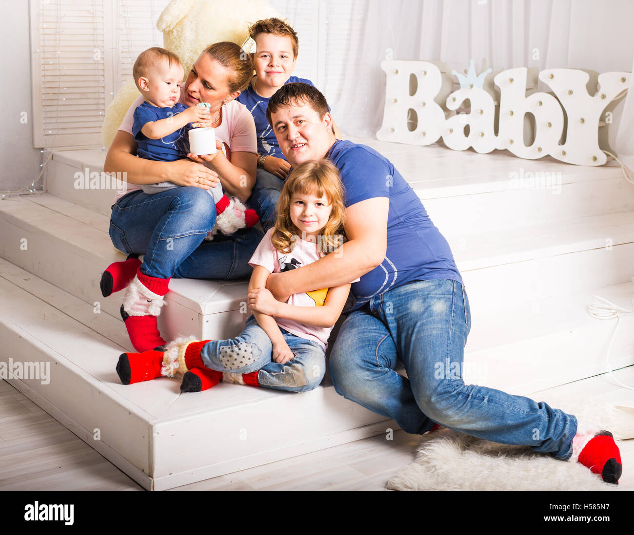 Happy family with 3 children sitting on floor of living room at home ...