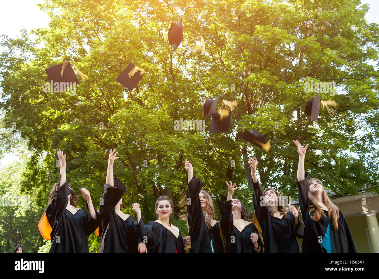 group of happy graduates throwing graduation hats in the air ...
