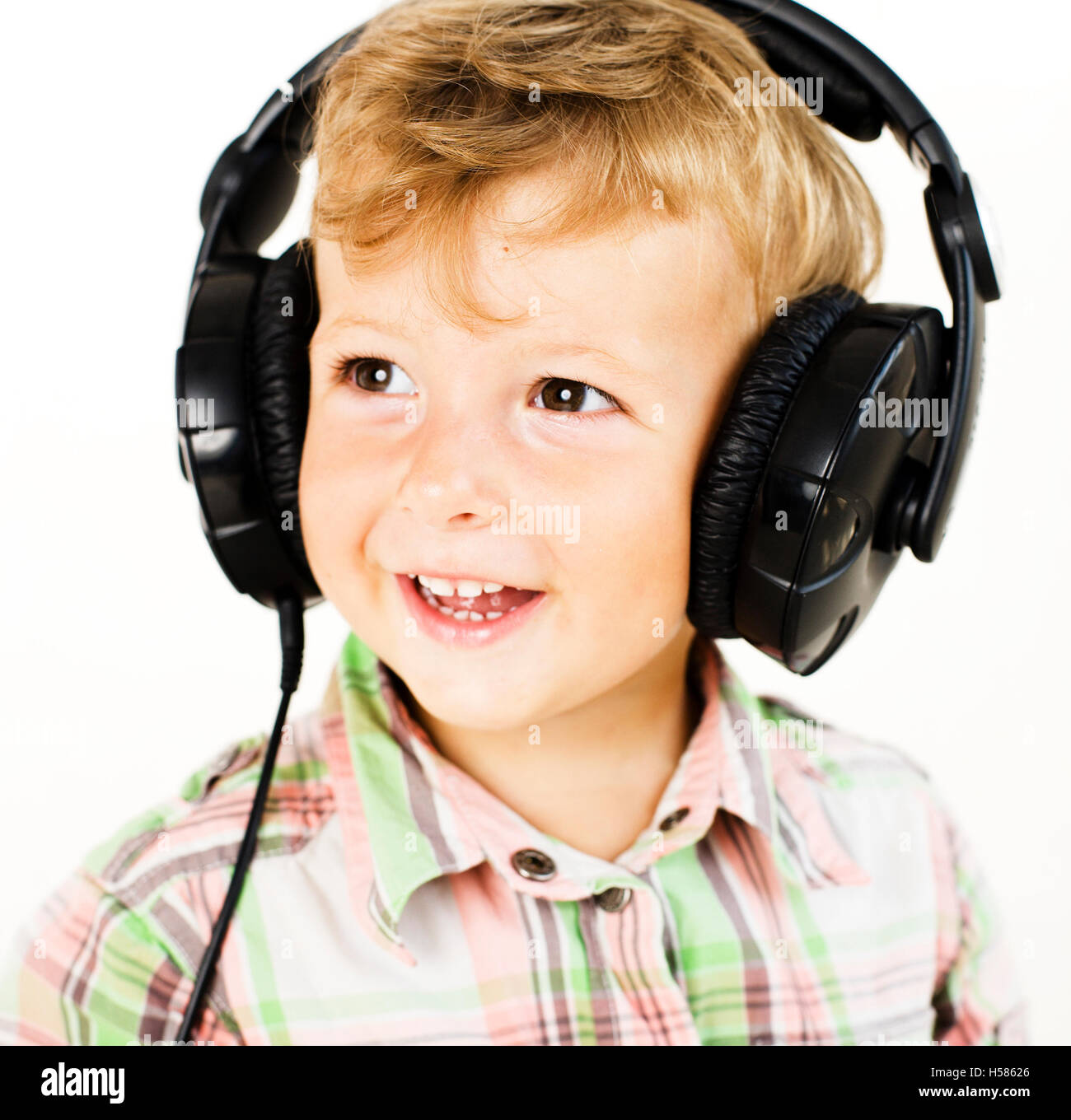 portrait of little cute boy in big earphones happy smiling isolated on ...