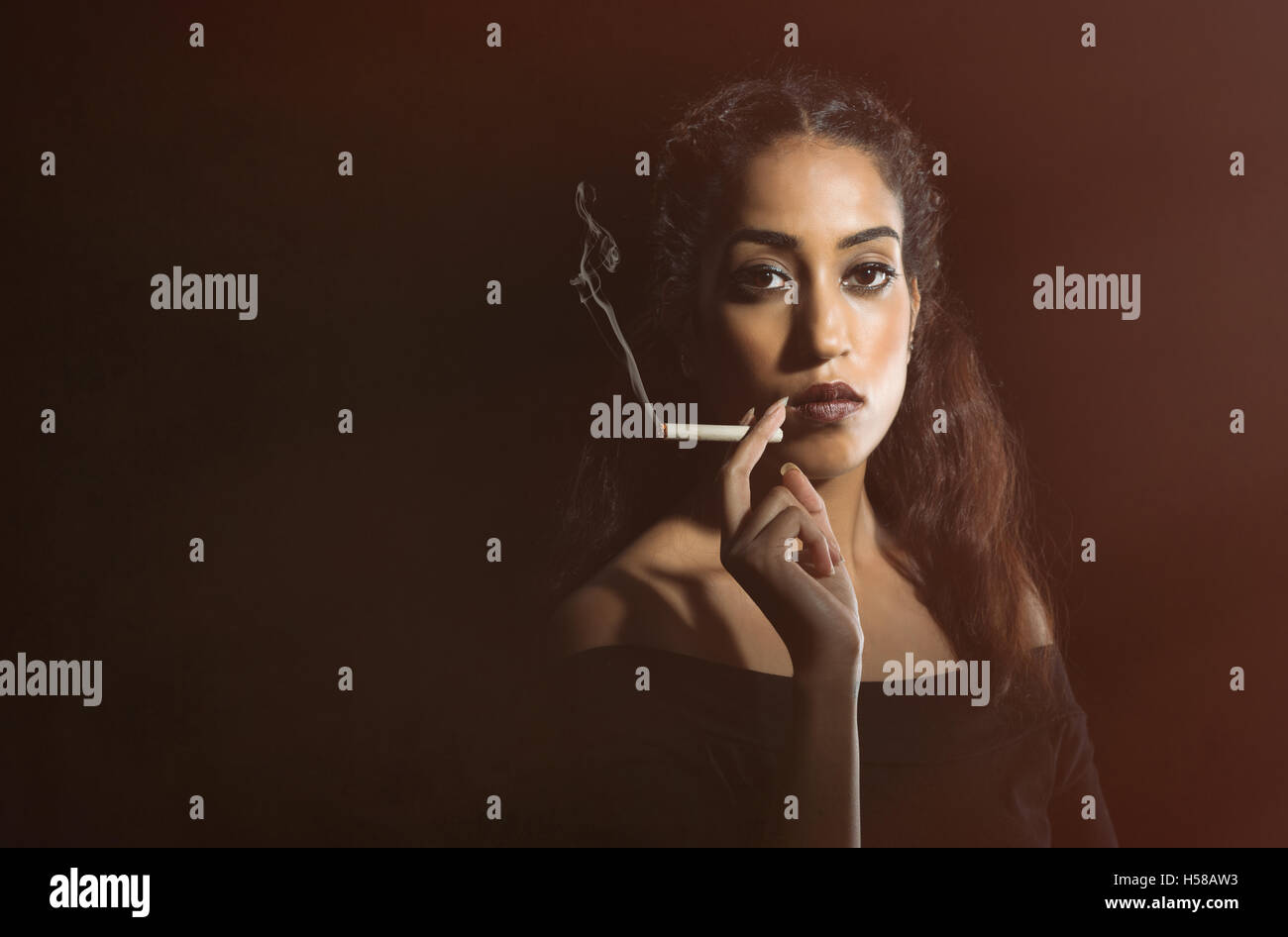 Portrait of a British Asian woman smoking a cigarette Stock Photo - Alamy
