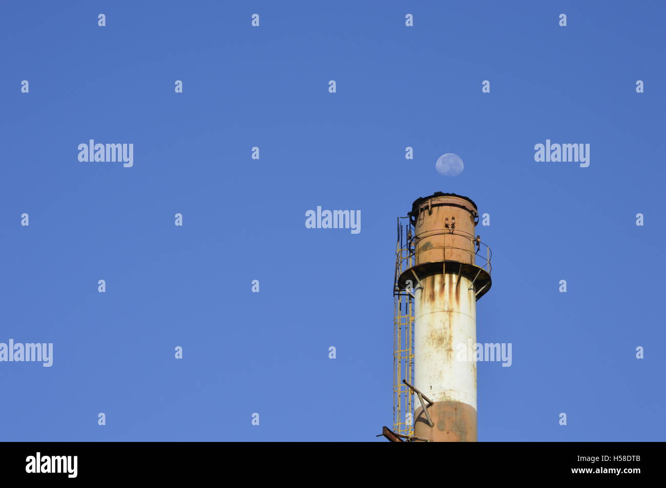 Industrial chimney and moon with blue sky background Stock Photo - Alamy