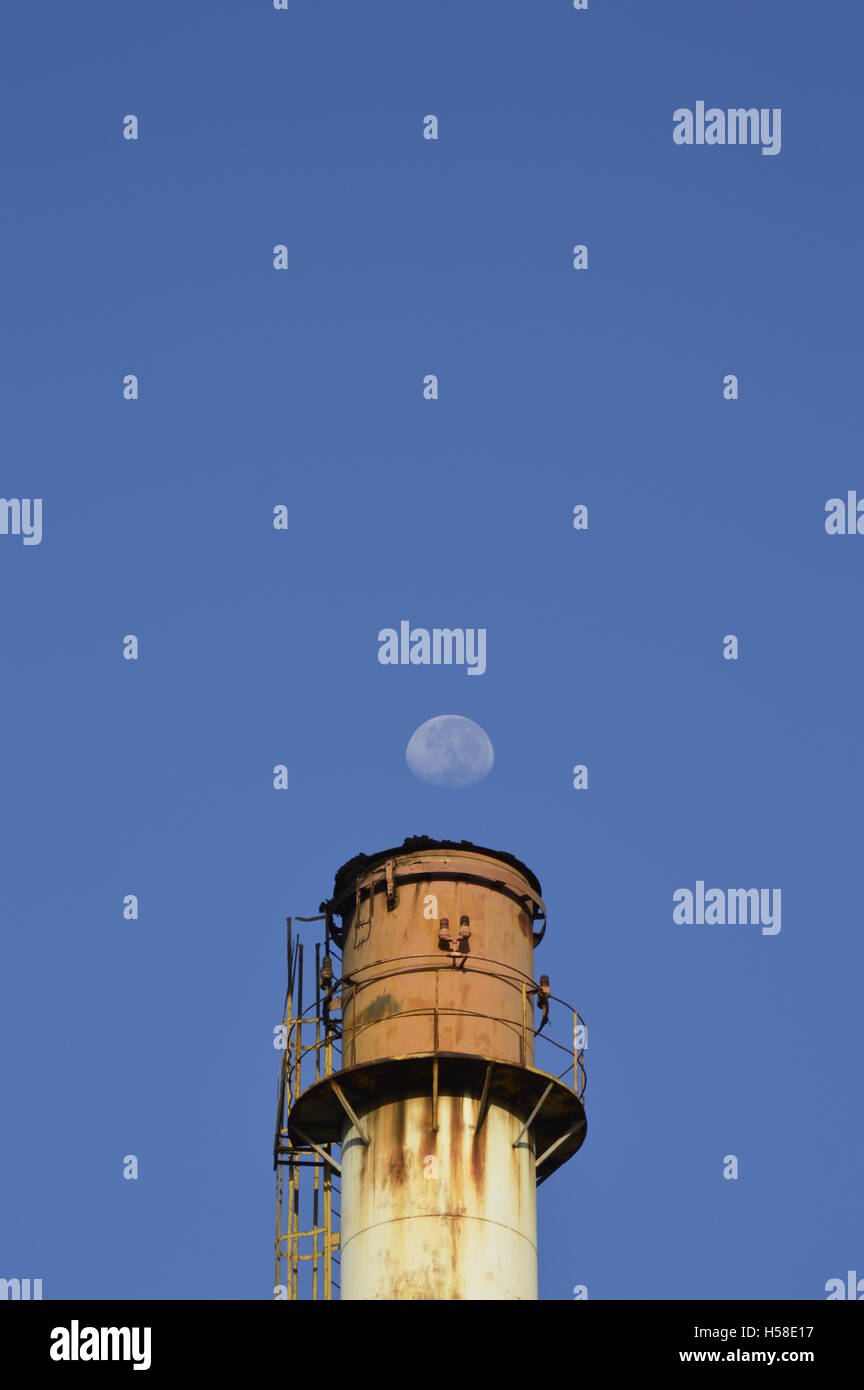 Industrial chimney and moon with blue sky background Stock Photo - Alamy