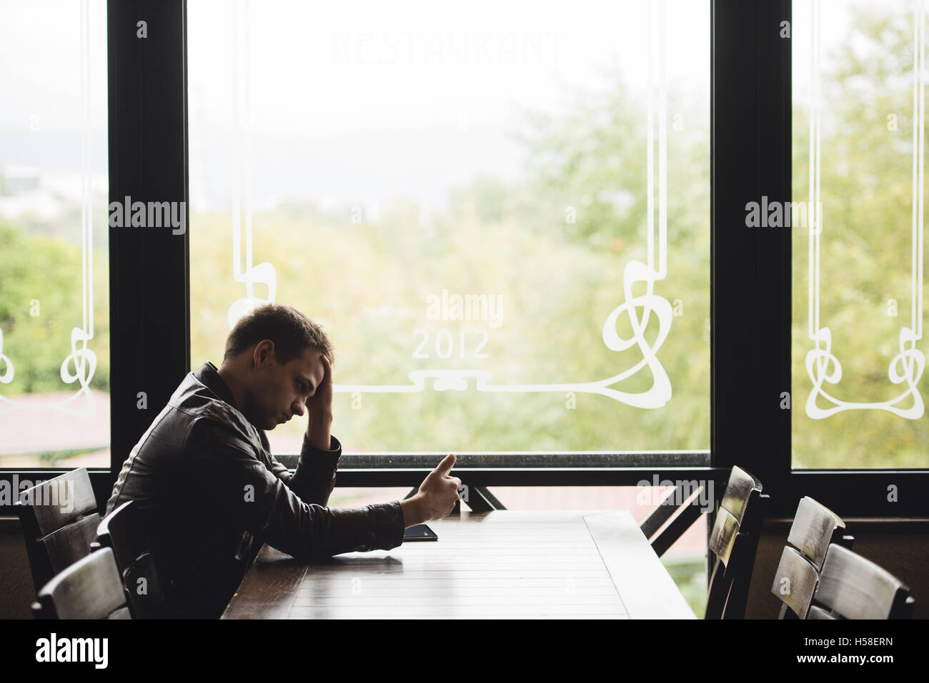 Portrait of tired young businessman typing on cellphone at cafe Stock ...
