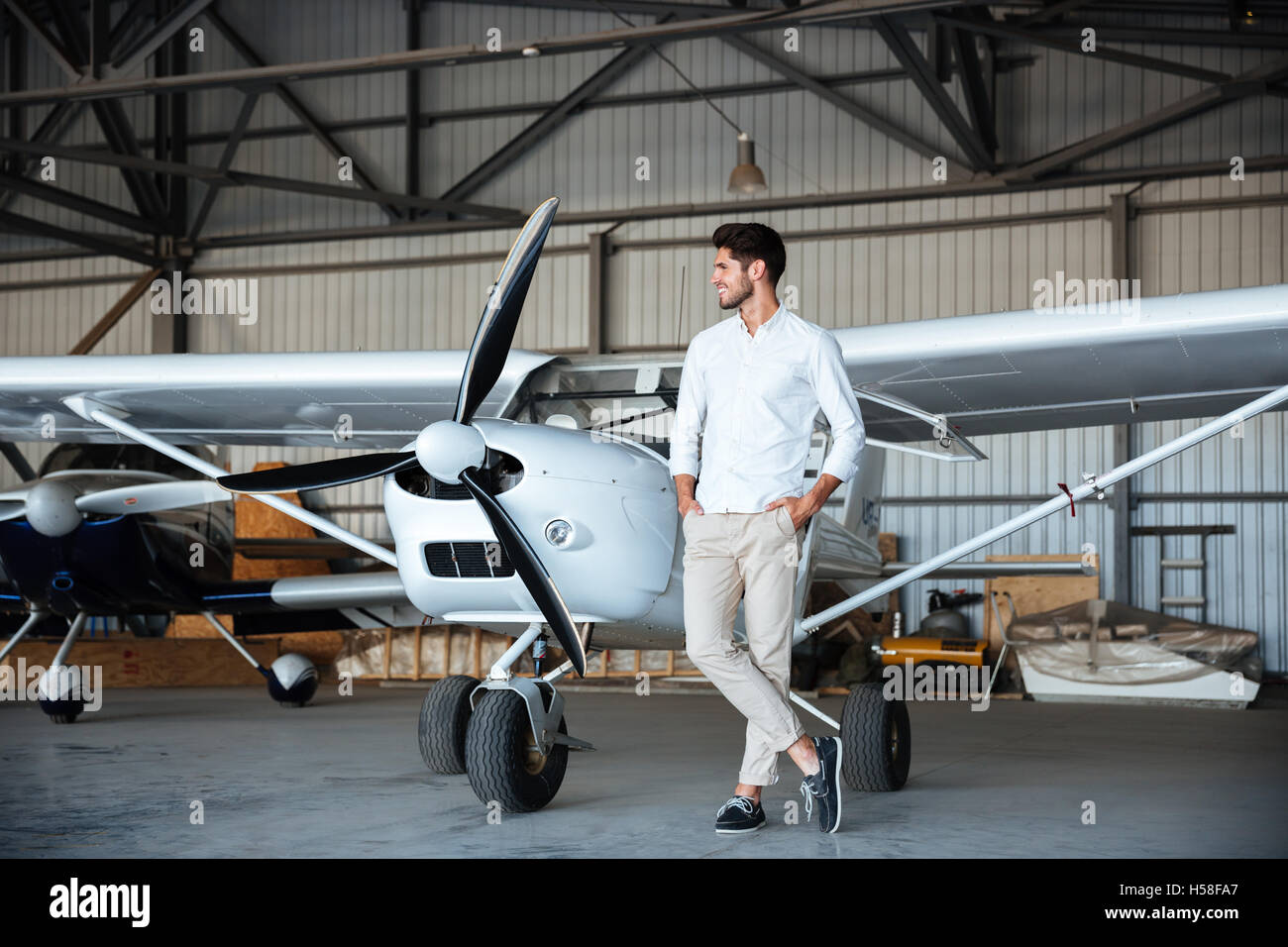 Full length of smiling young man standing near small aircraft Stock ...