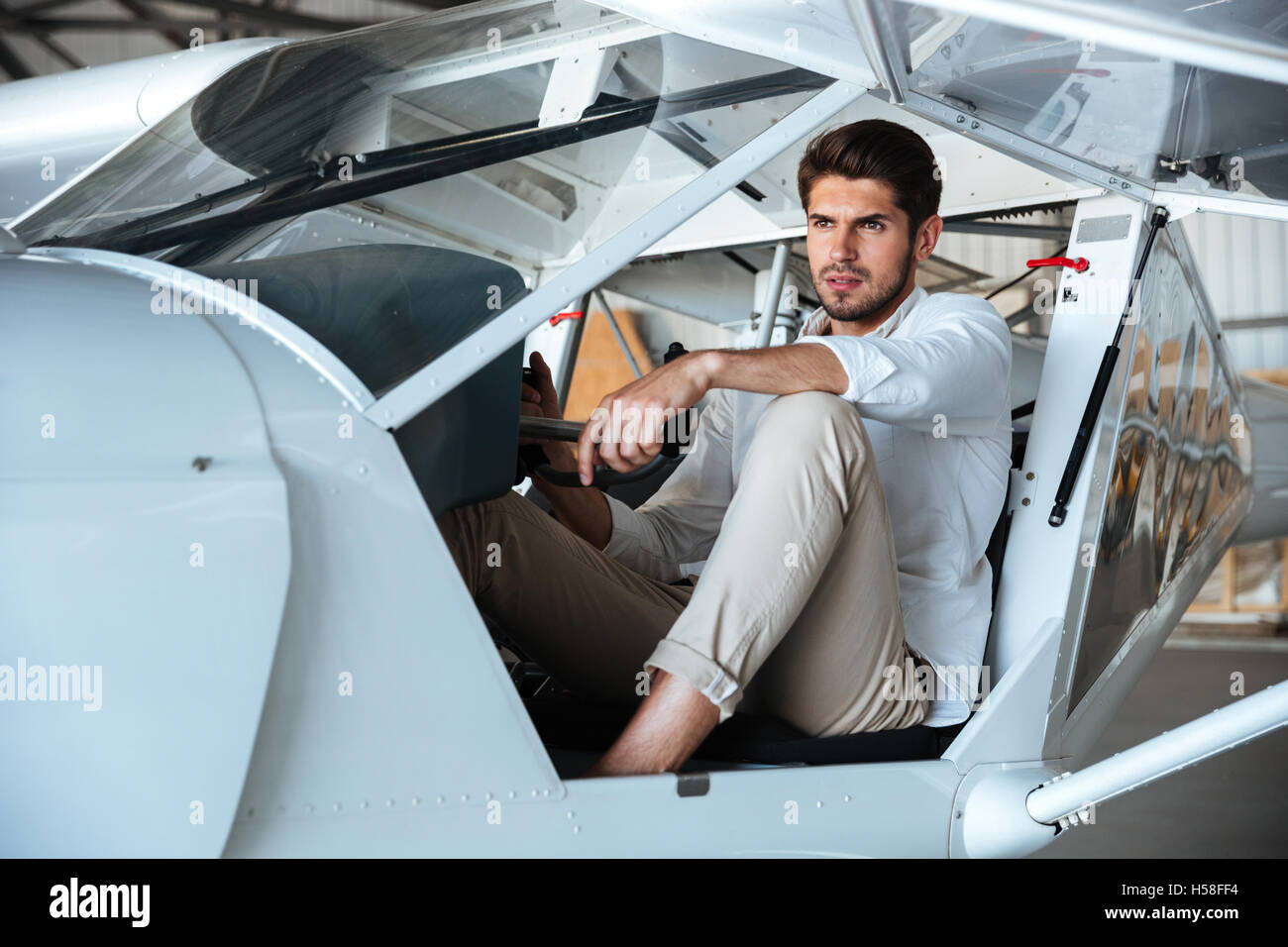 Portrait of attractive young man pilot in small aircraft Stock Photo ...