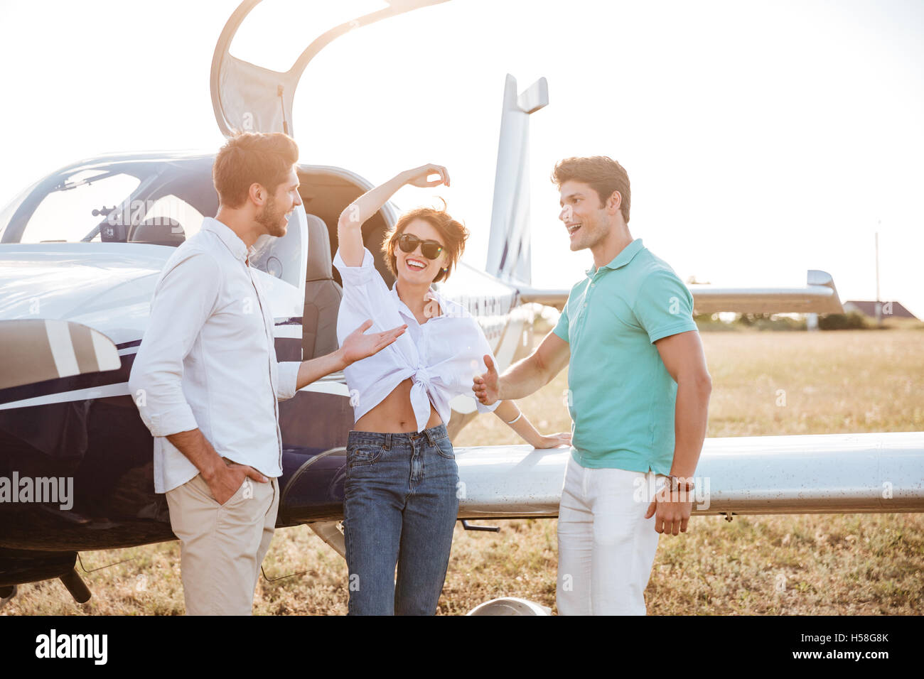 Group of three cheerful young friends standing and talking on runway ...
