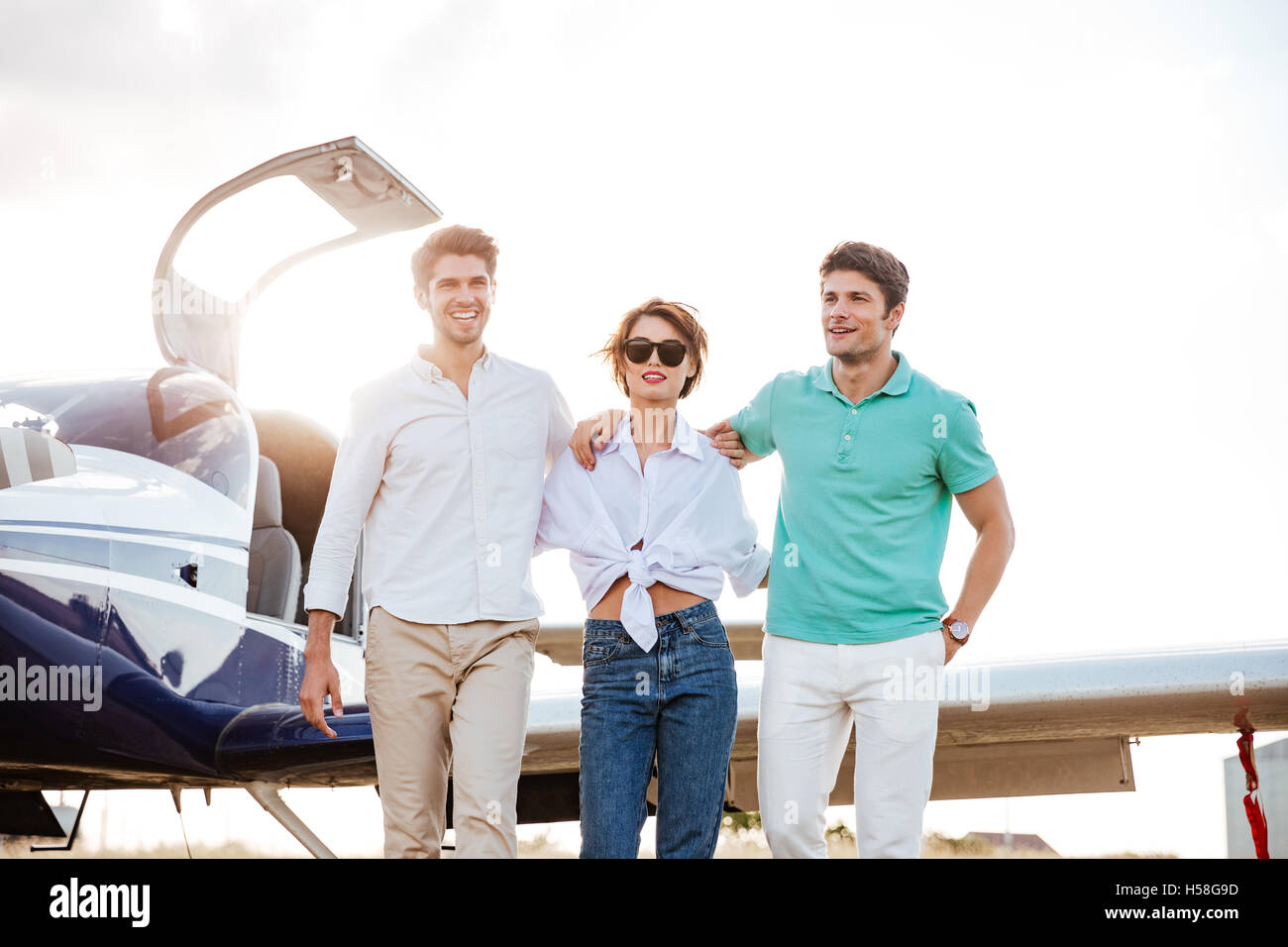 Group of happy young friends walking together on runway in airport ...