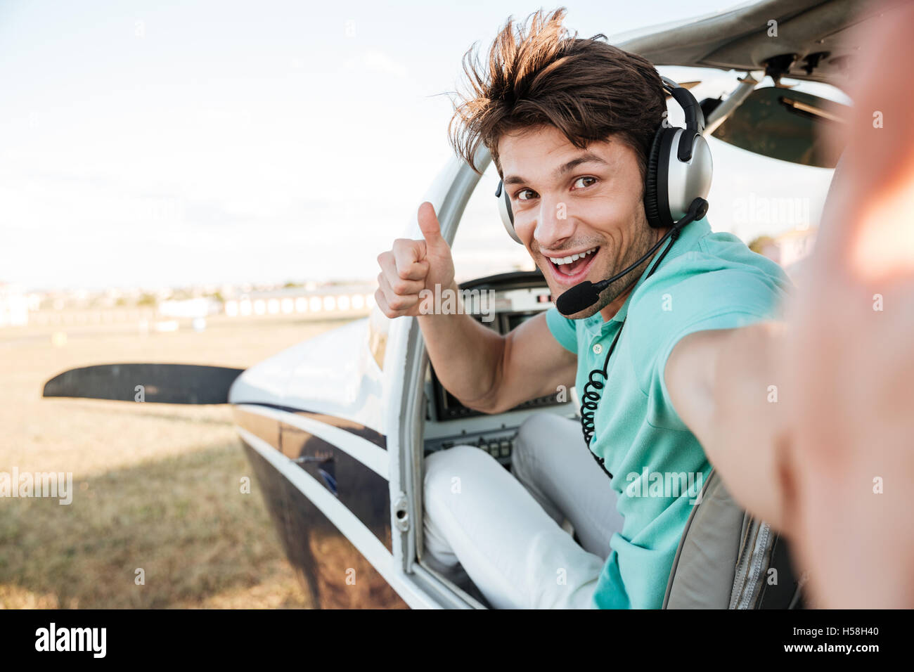 Cheerful excited young pilot sitting in cabin of small airplane and ...