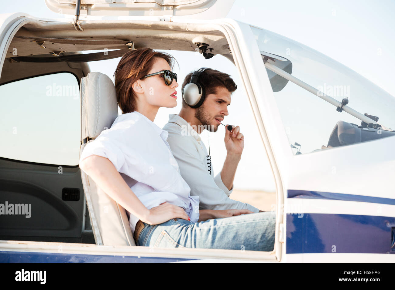 Young pilot and beautiful stewardess sitting together inside airplane ...