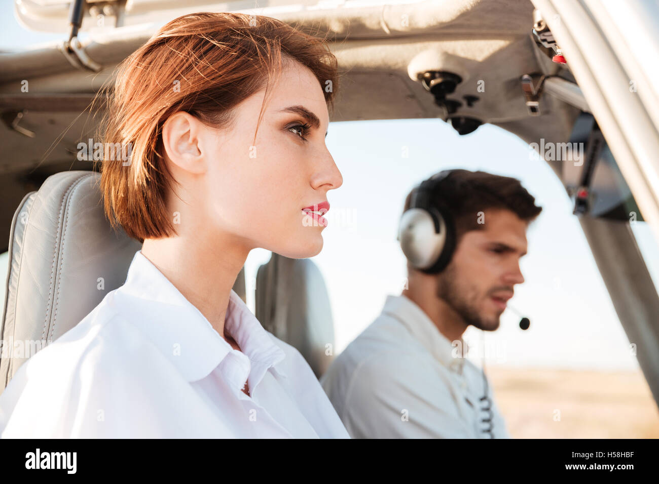 Close up portrait of a young pilot and beautiful stewardess sitting ...