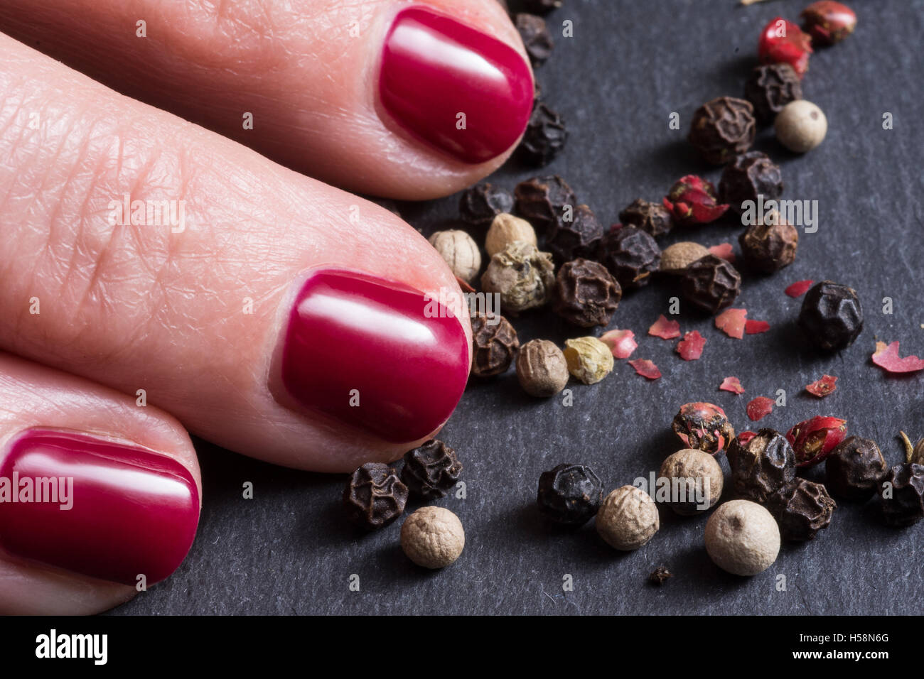 Painted Nails and Pepper Grains on Dark Stone Surface Close Up Stock ...