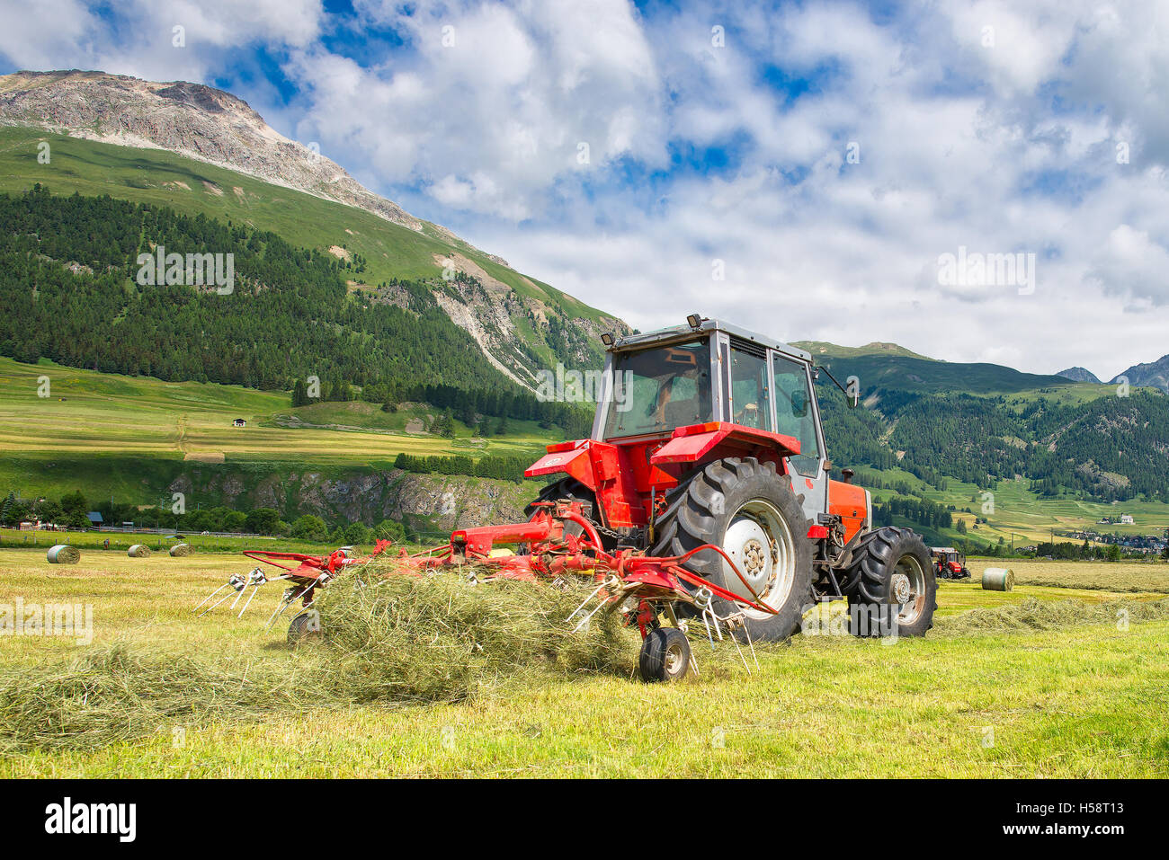 Scatter hay tractor works in meadows of the Swiss Alps Stock Photo - Alamy